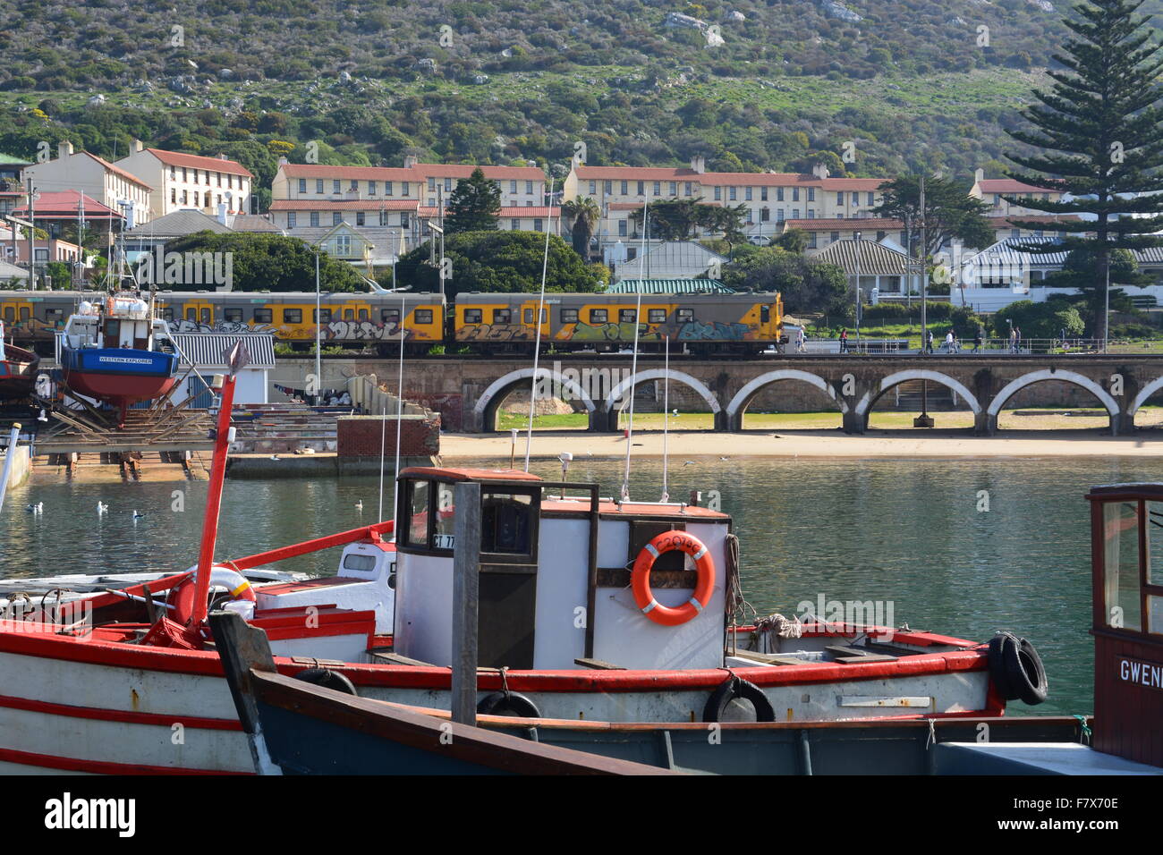 Cape Town Metrorail train passing behind fishing boats at harbor in ...