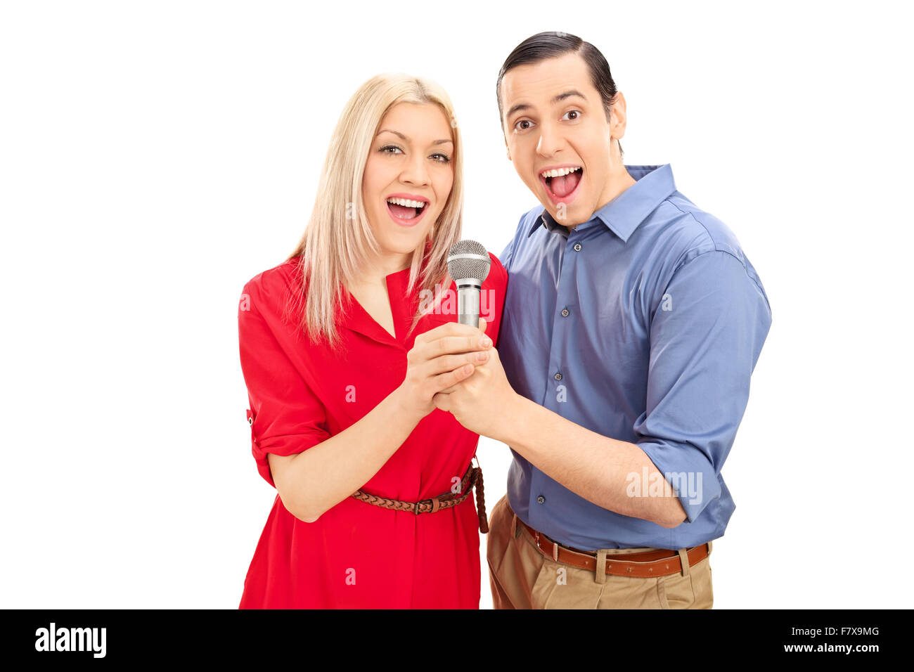 Young joyful couple singing on microphone together isolated on white ...