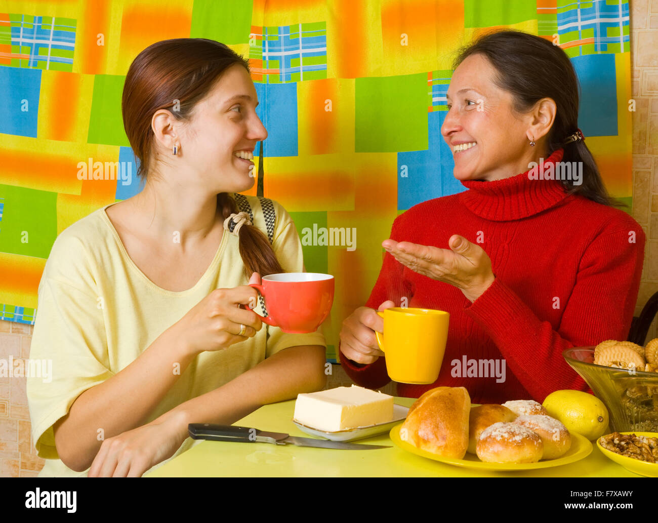 Two smiling women talking in kitchen with tea Stock Photo - Alamy