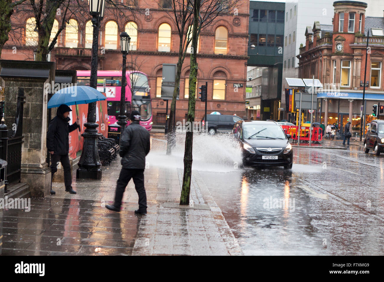 Belfast, UK. 3rd Dec, 2015. Pedestrians gets splashed by a car driving ...