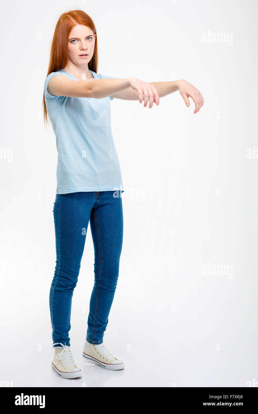 Amusing pretty young woman standing and posing like a zombie isolated ...