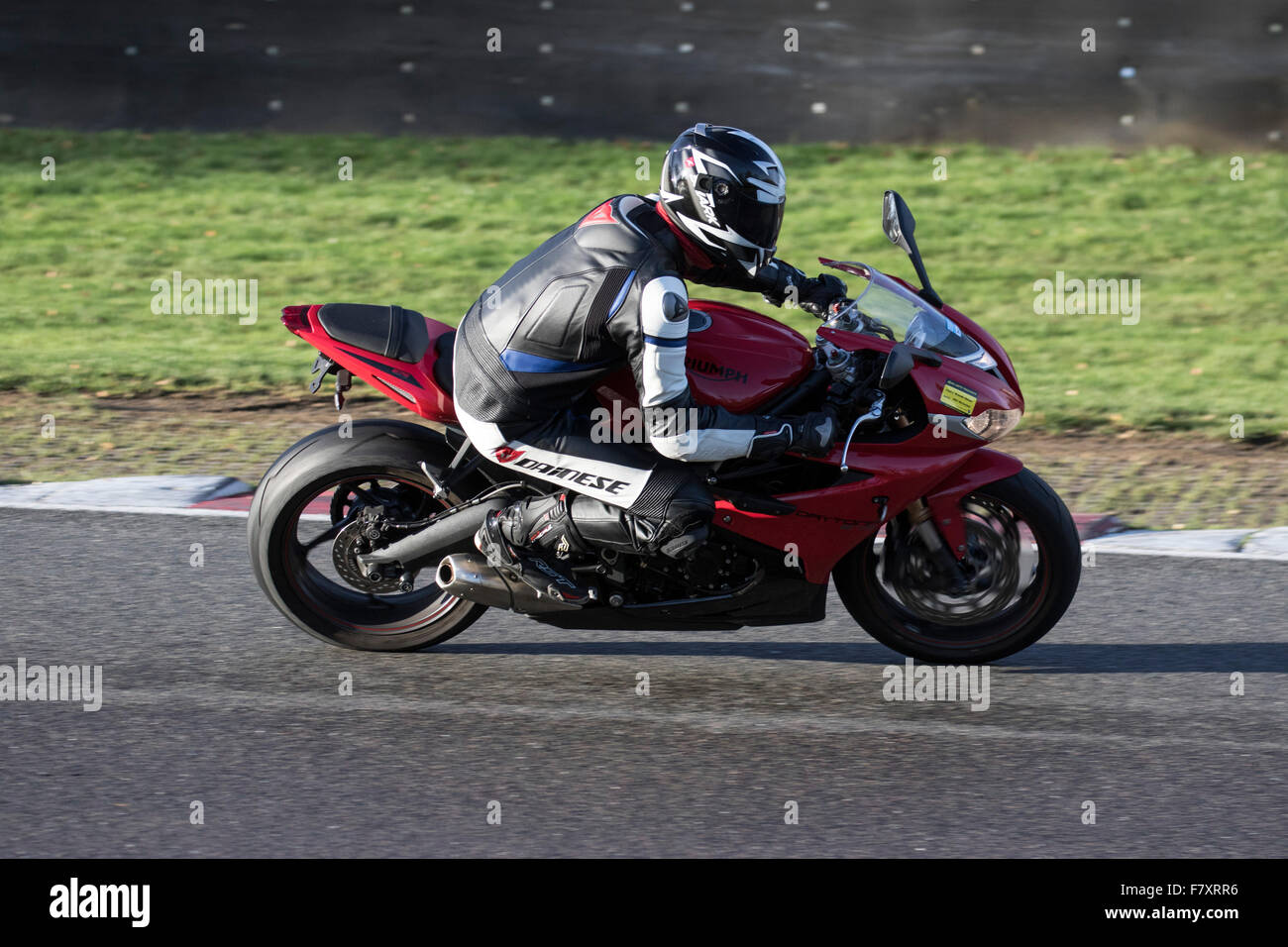A red Triumph Daytona 675 motorcycle leaving Druids Corner at Brands ...