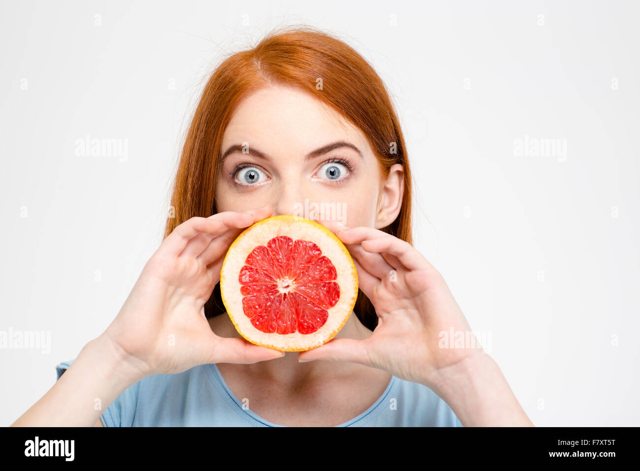 Portrait of shocked amusing young lady with red hair holding half of ...