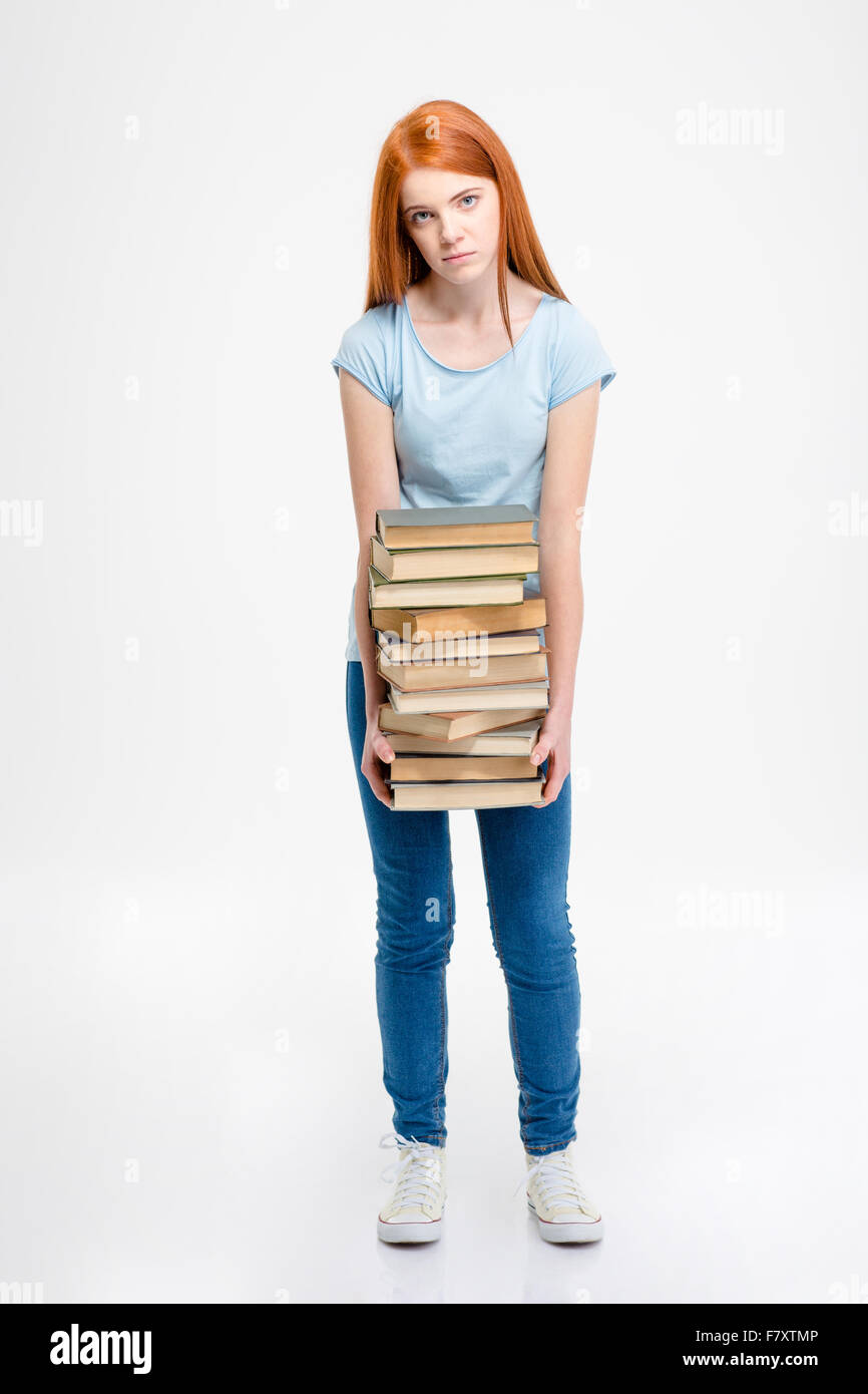 Tired exhausted young redhead woman standing and holding stack of books ...
