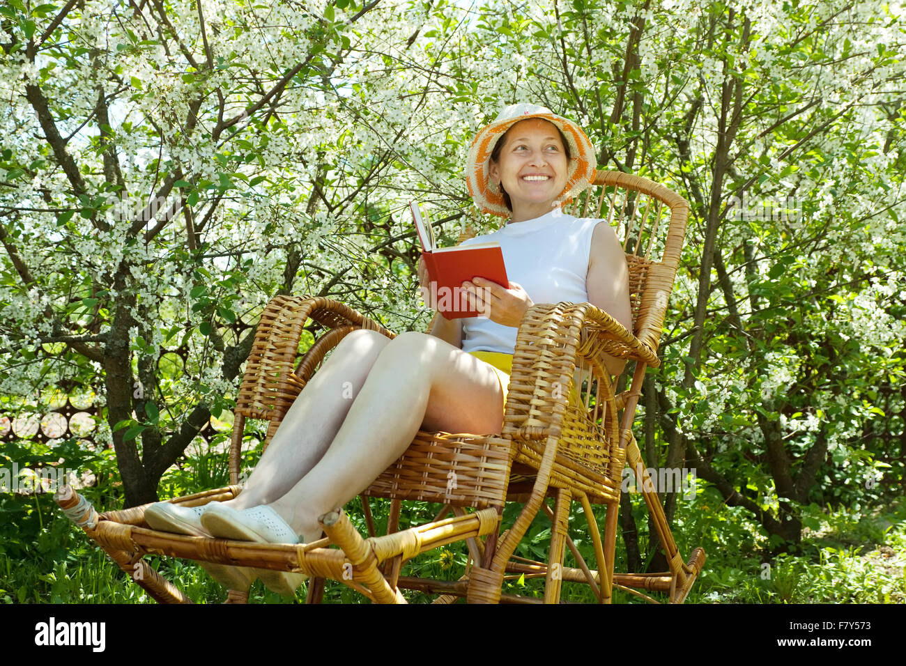 Relaxing mature woman in rocking-chair against bloom garden Stock Photo ...