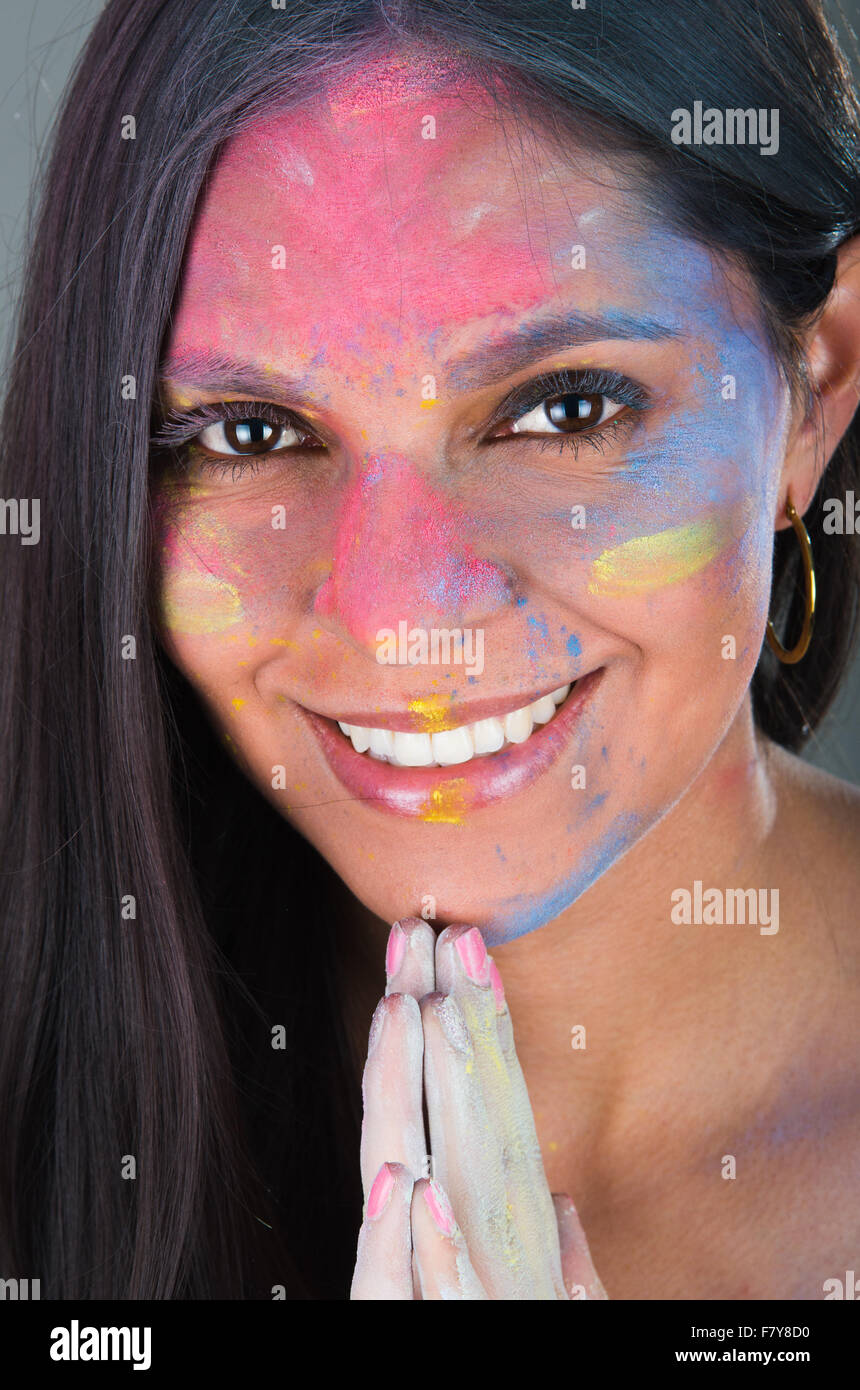 Beautiful young brunette girl with colorful decorated face praying ...