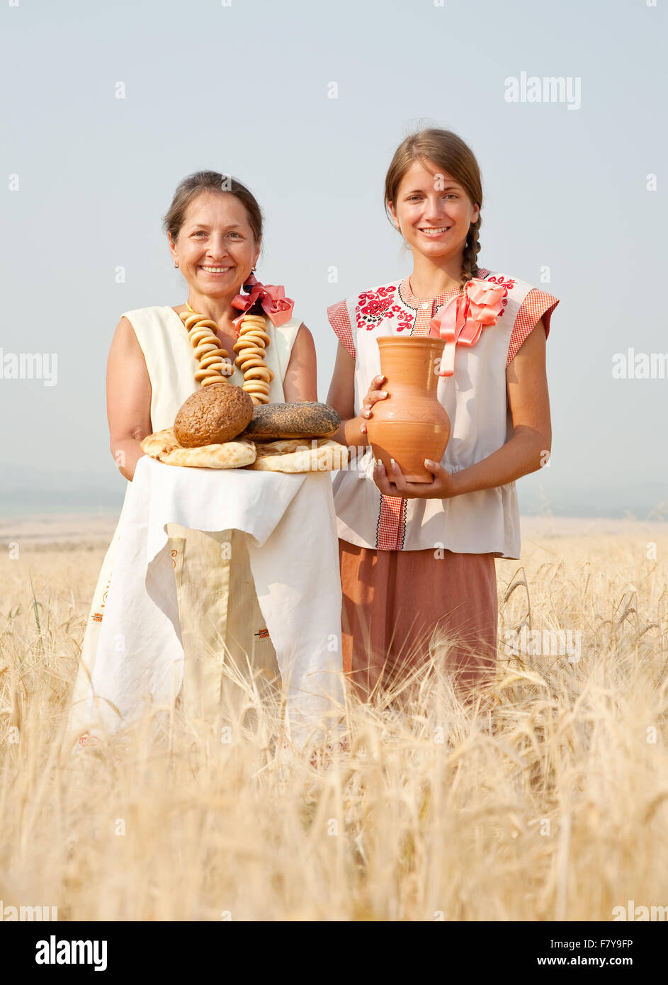 Women in traditional clothes with bread at cereals field Stock Photo ...
