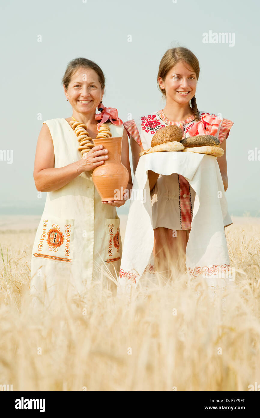 Women in traditional clothes with bread at cereals field Stock Photo ...
