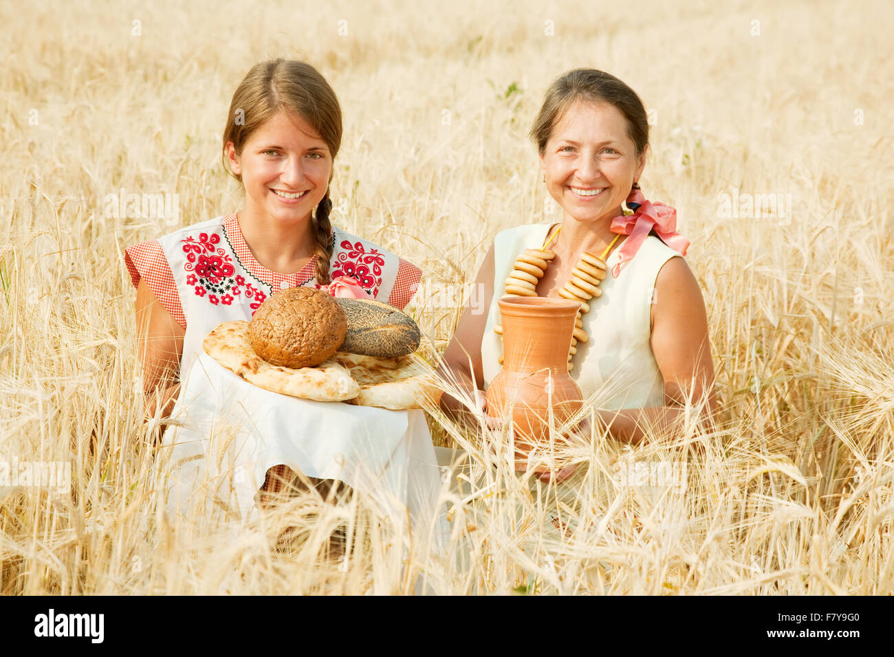 Women in traditional clothes with bread at cereals field Stock Photo ...
