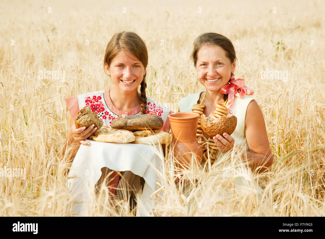 Women in traditional clothes with bread at cereals field Stock Photo ...