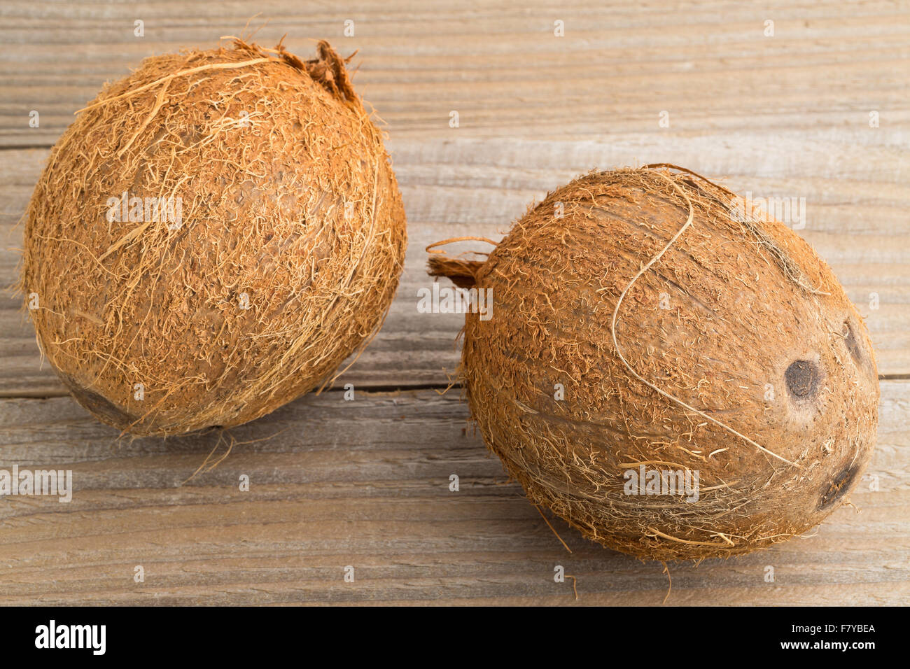 Two whole uncut coconuts on wooden table background Stock Photo - Alamy