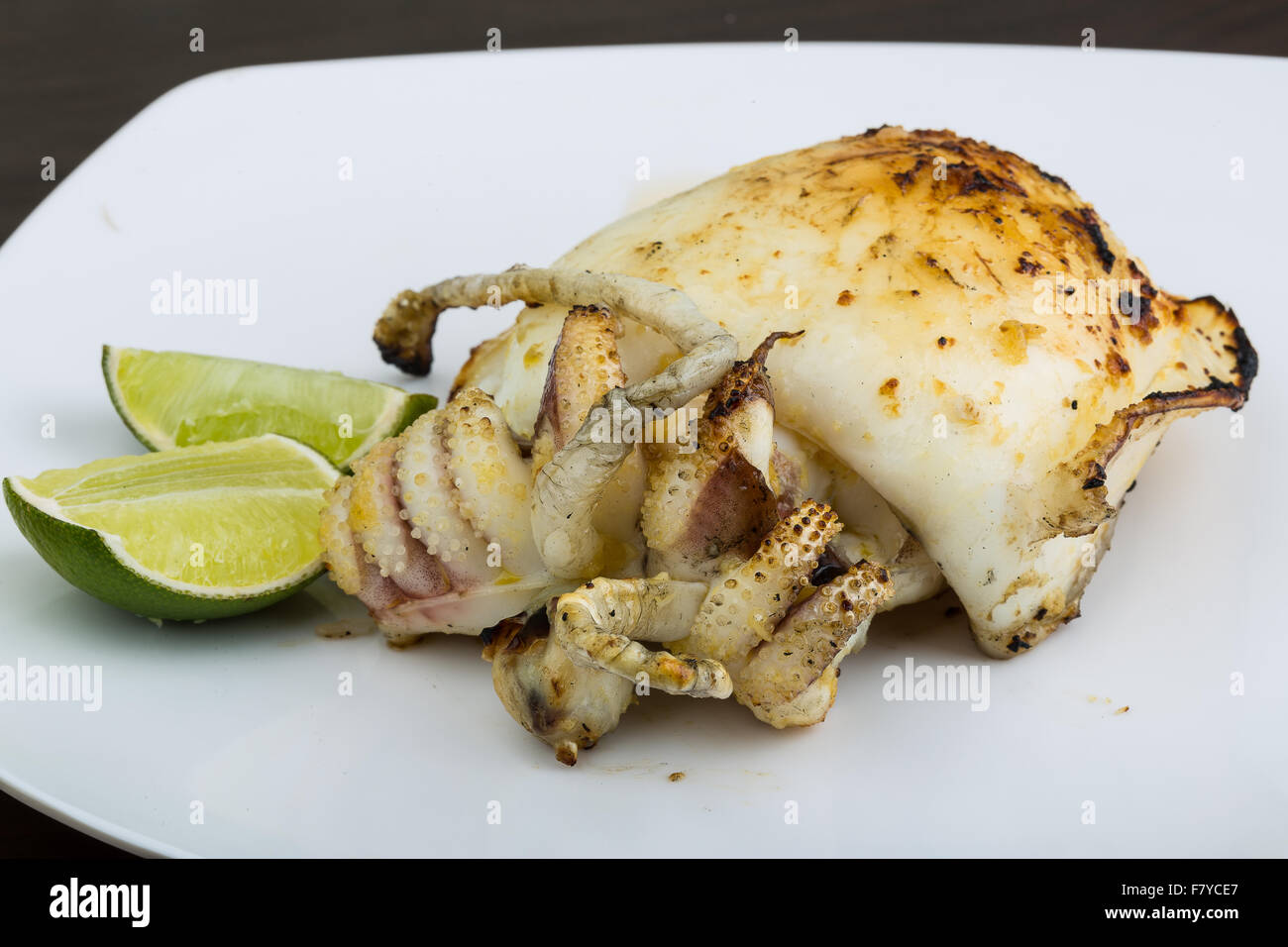 Grilled cuttlefish with lime on the wooden background Stock Photo - Alamy
