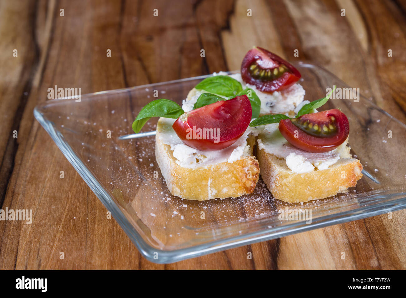 small bite size appetizer with goat cheese and tomato on a piece of ...