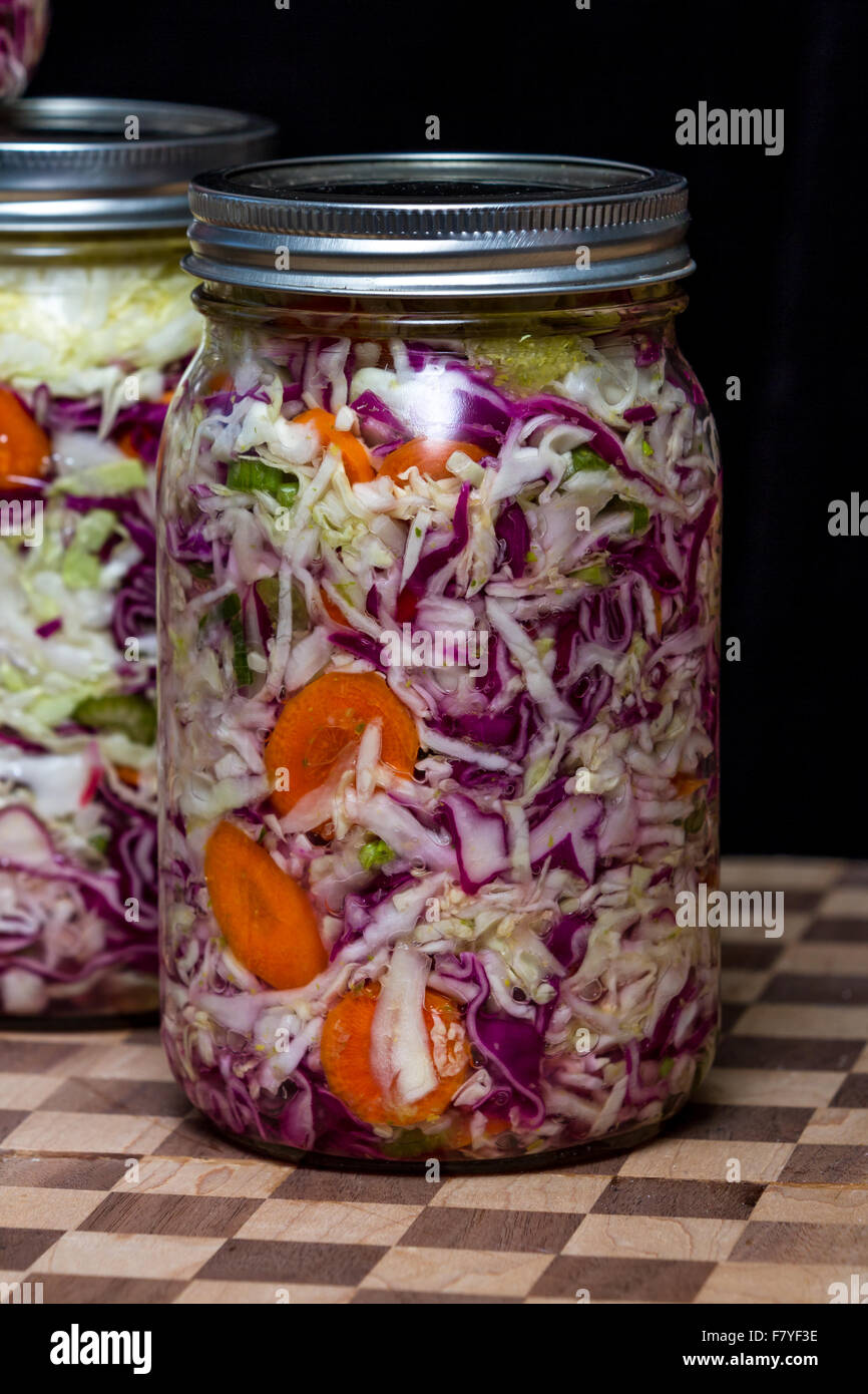 home made cultured or fermented vegetables in a jar over a dark ...