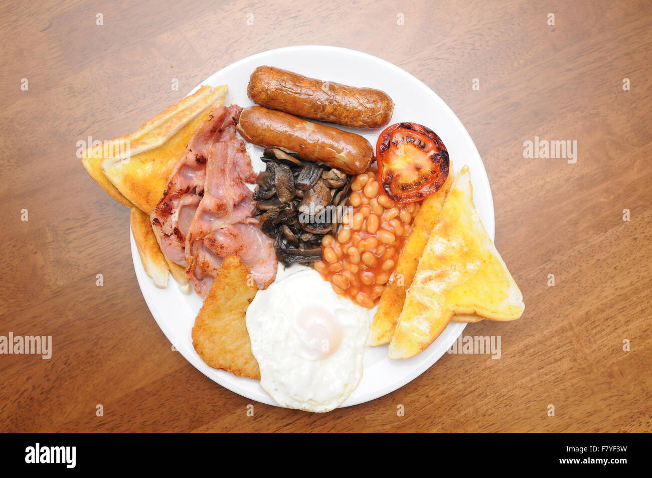 Traditional England fried breakfast with sausages, fried tomato, eggs ...