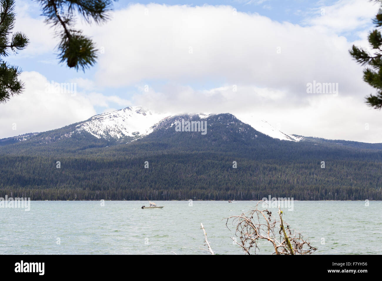fishing boat in a choppy lake with Diamond peak capped with snow and ...