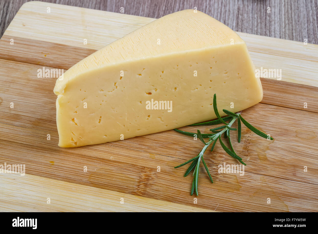 Yellow cheese triangle with rosemary herbs on the wood background Stock ...