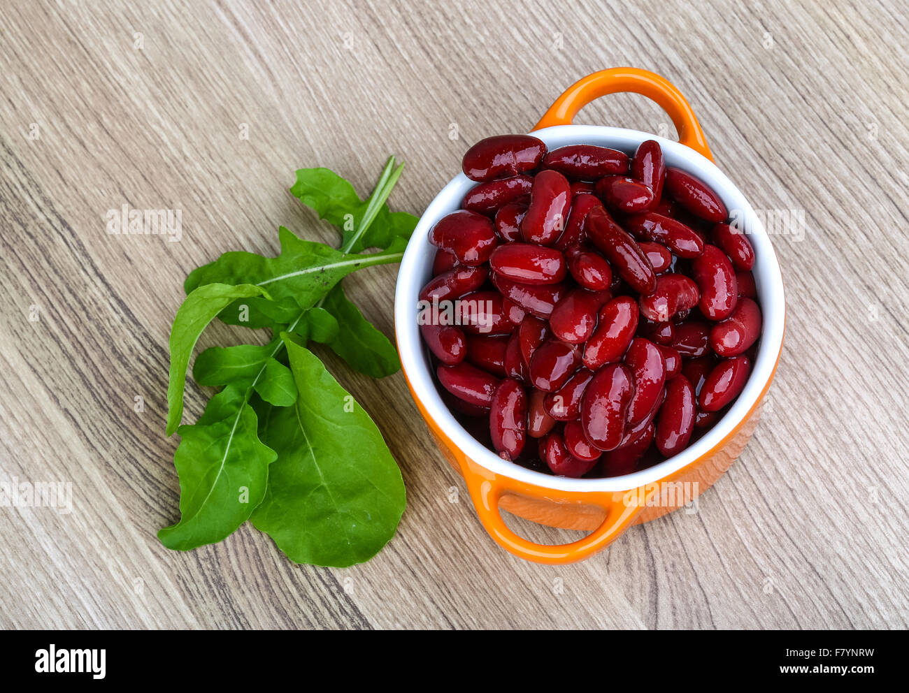 Red kidney on the bowl with ruccola leaves wood background Stock Photo ...