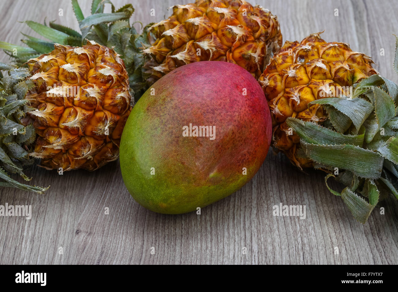Mini pineapple and mango fruit on the wood background Stock Photo - Alamy