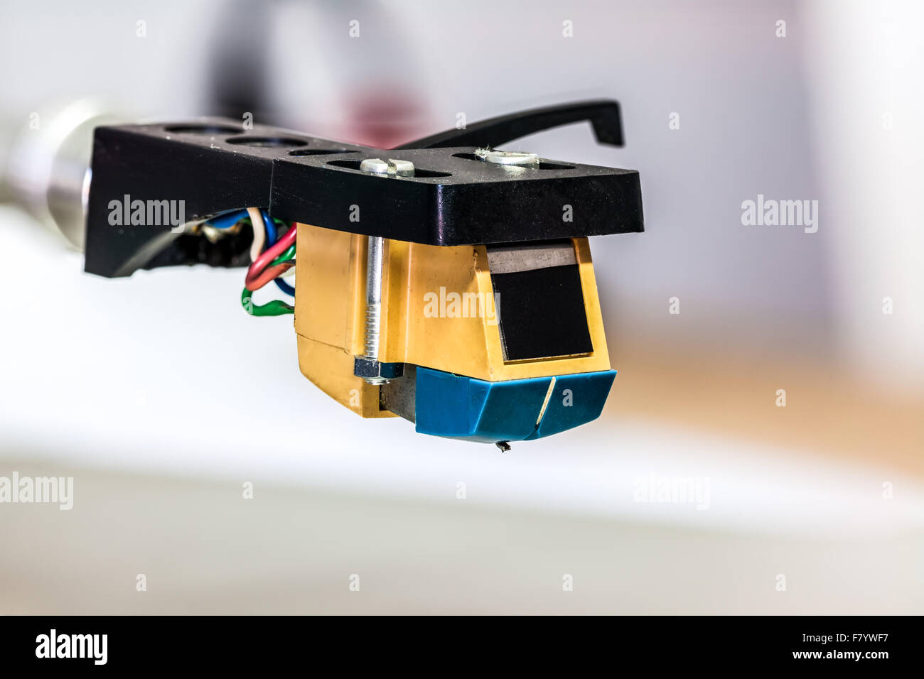 an arm of a record player with a steel needle that converts sound waves ...
