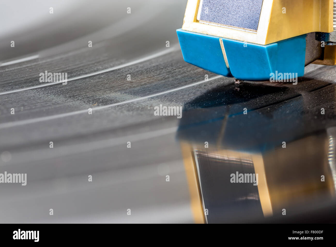 an arm of a record player with a steel needle that converts sound waves ...