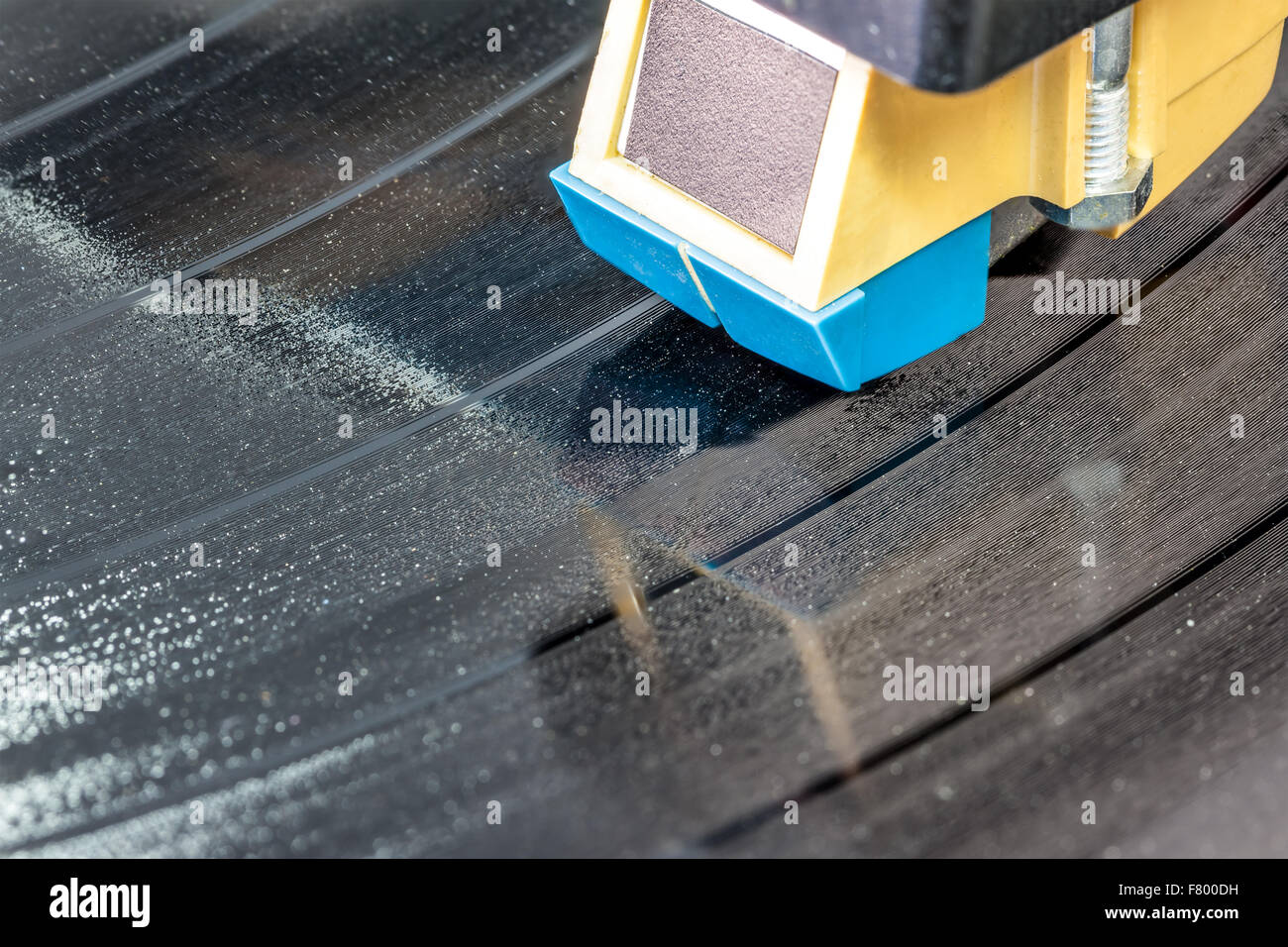 an arm of a record player with a steel needle that converts sound waves ...