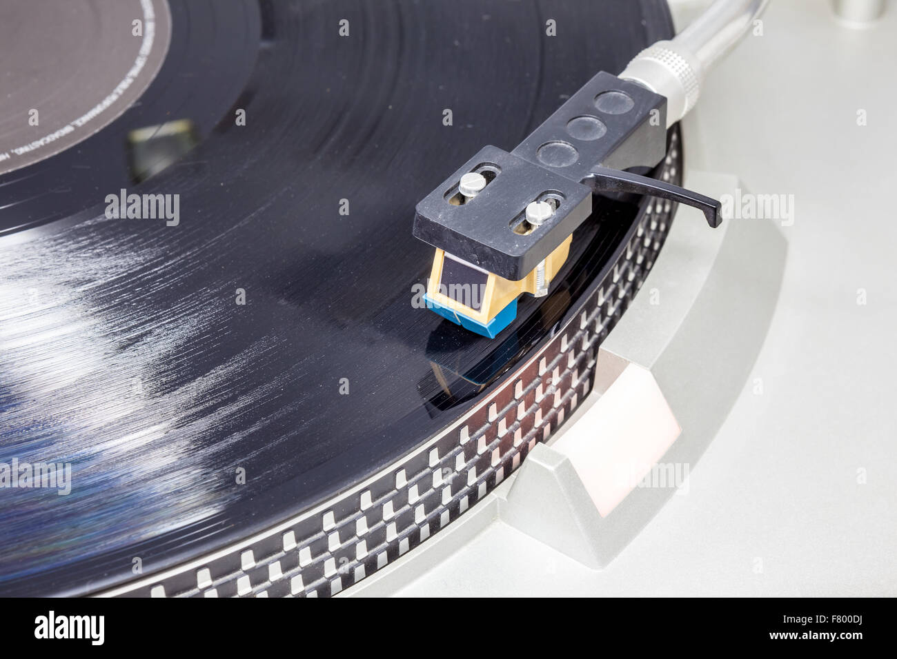 an arm of a record player with a steel needle that converts sound waves ...