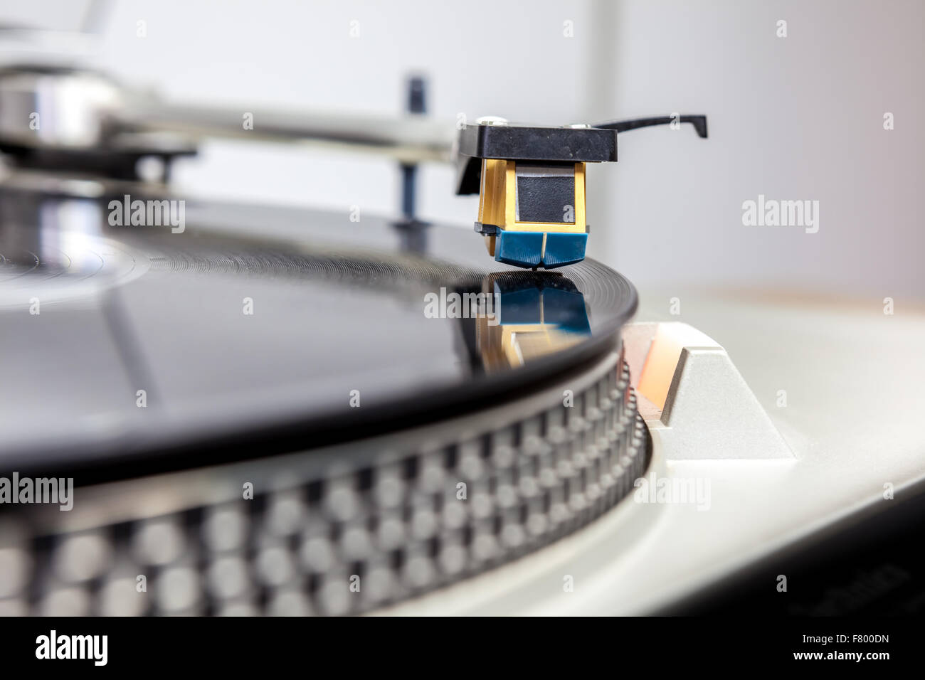 an arm of a record player with a steel needle that converts sound waves ...