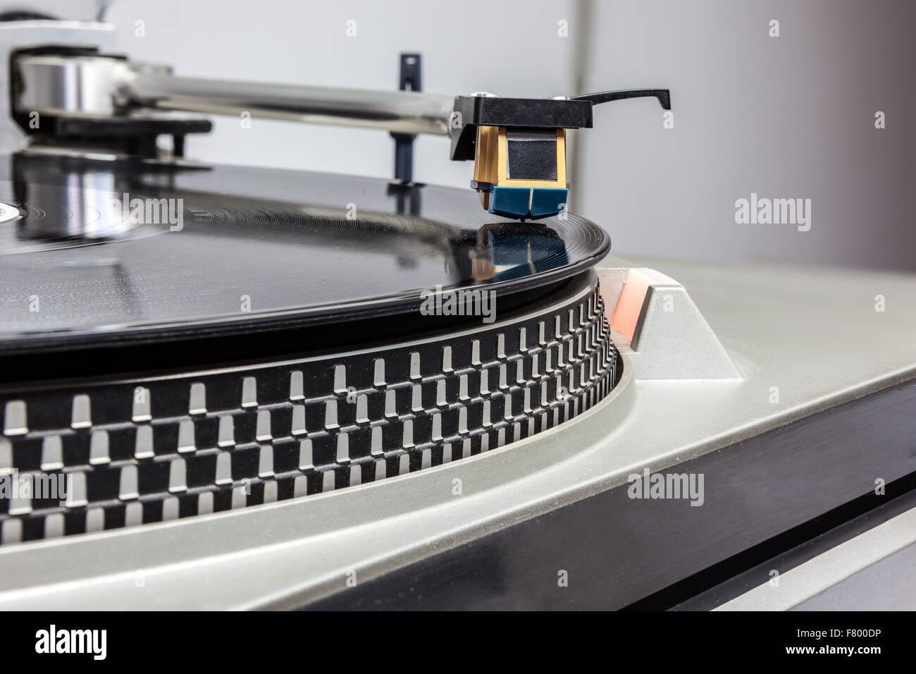 an arm of a record player with a steel needle that converts sound waves ...