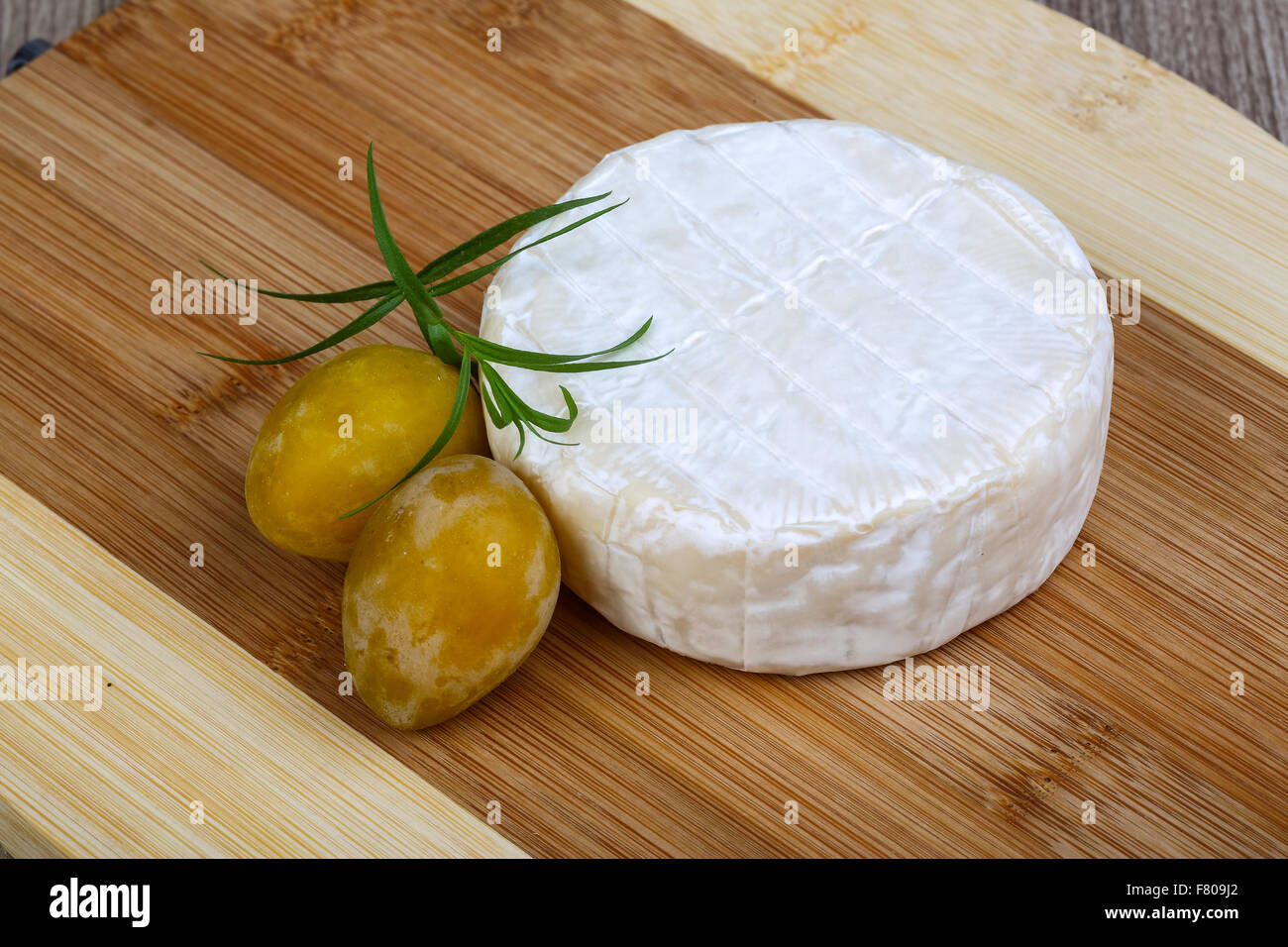 Round Brie cheese with yellow plums and estragon Stock Photo - Alamy