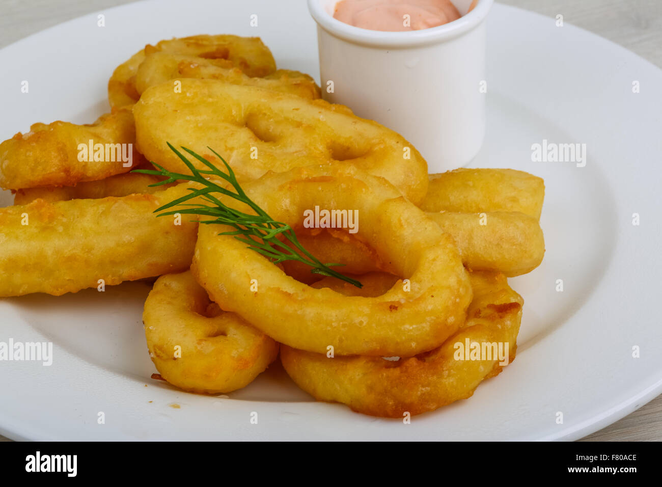 Fried calamari rings with sauce and dill Stock Photo - Alamy