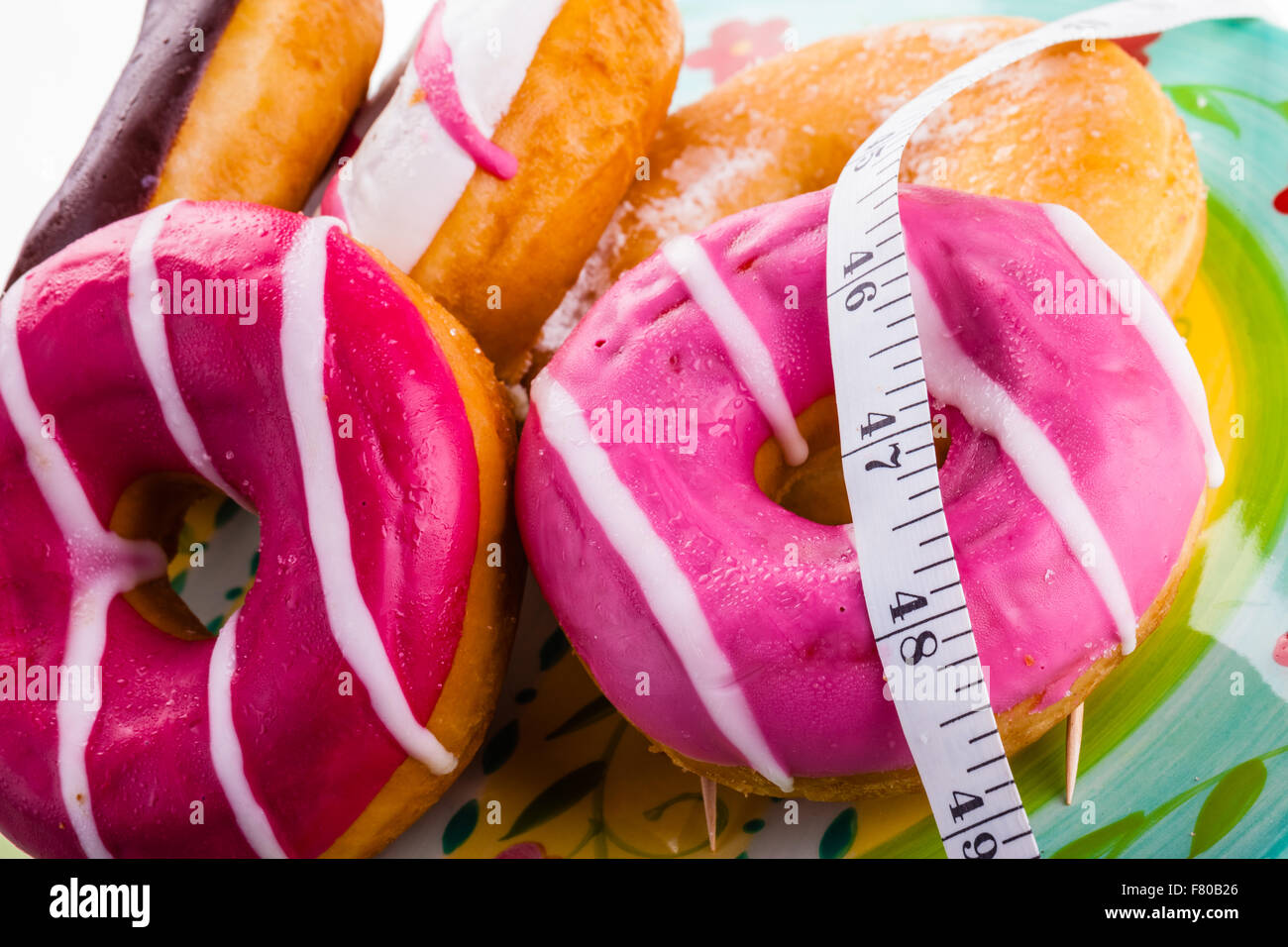 some delicious and colorful donuts with measuring tape Stock Photo - Alamy