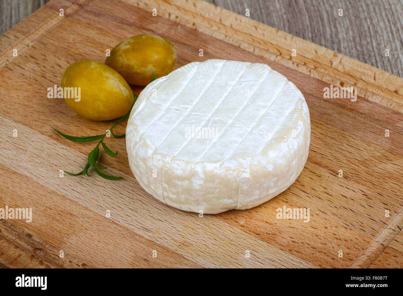 Round Brie cheese with yellow plums and estragon Stock Photo - Alamy