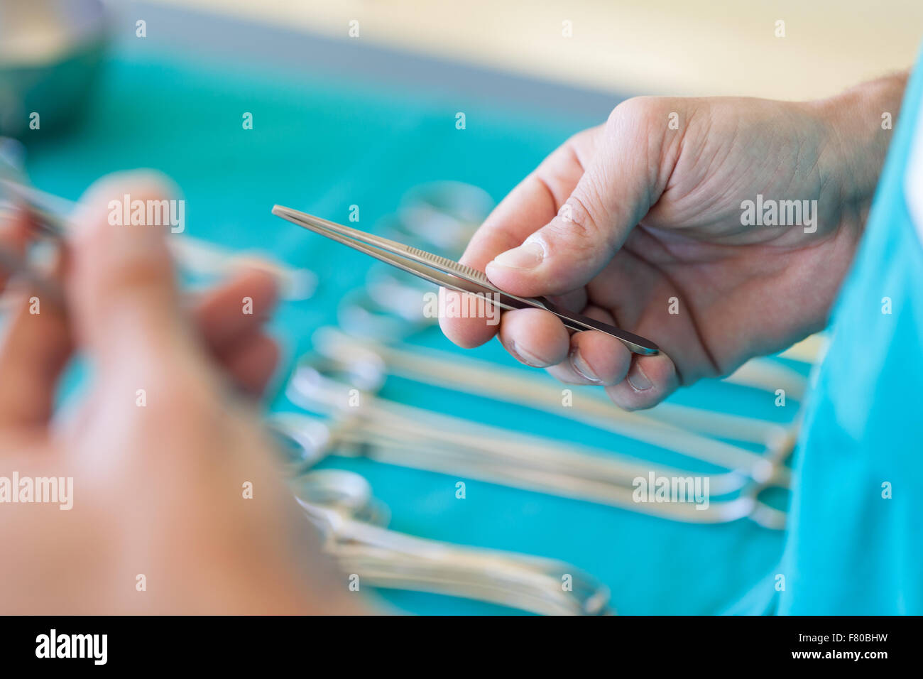 the hands of a surgeon holding two tweezers Stock Photo - Alamy