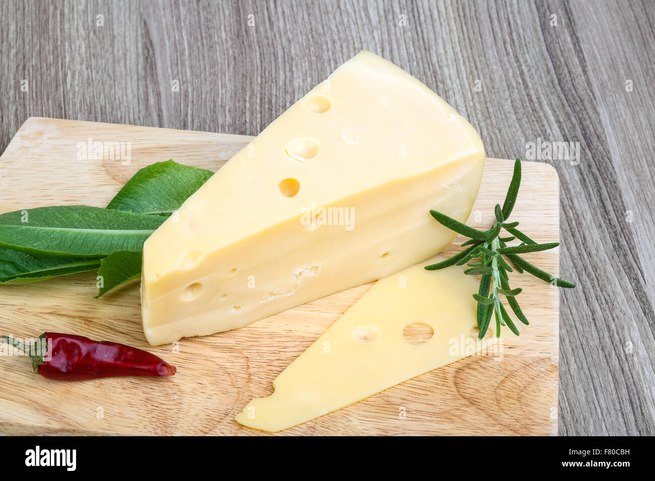Triangle yellow cheese with rosemary, pepper and salad leaves Stock ...
