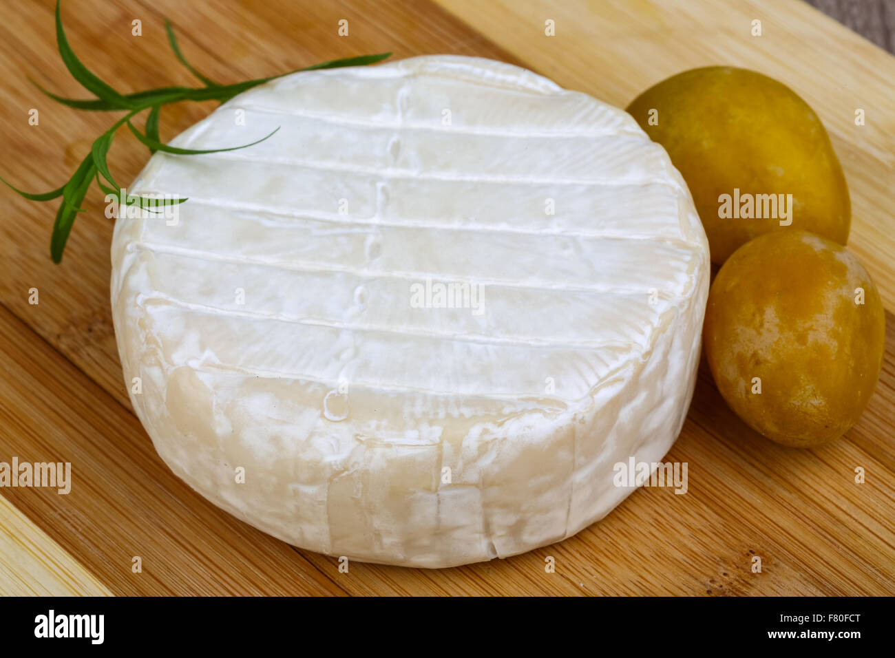 Round Brie cheese with yellow plums and estragon Stock Photo - Alamy