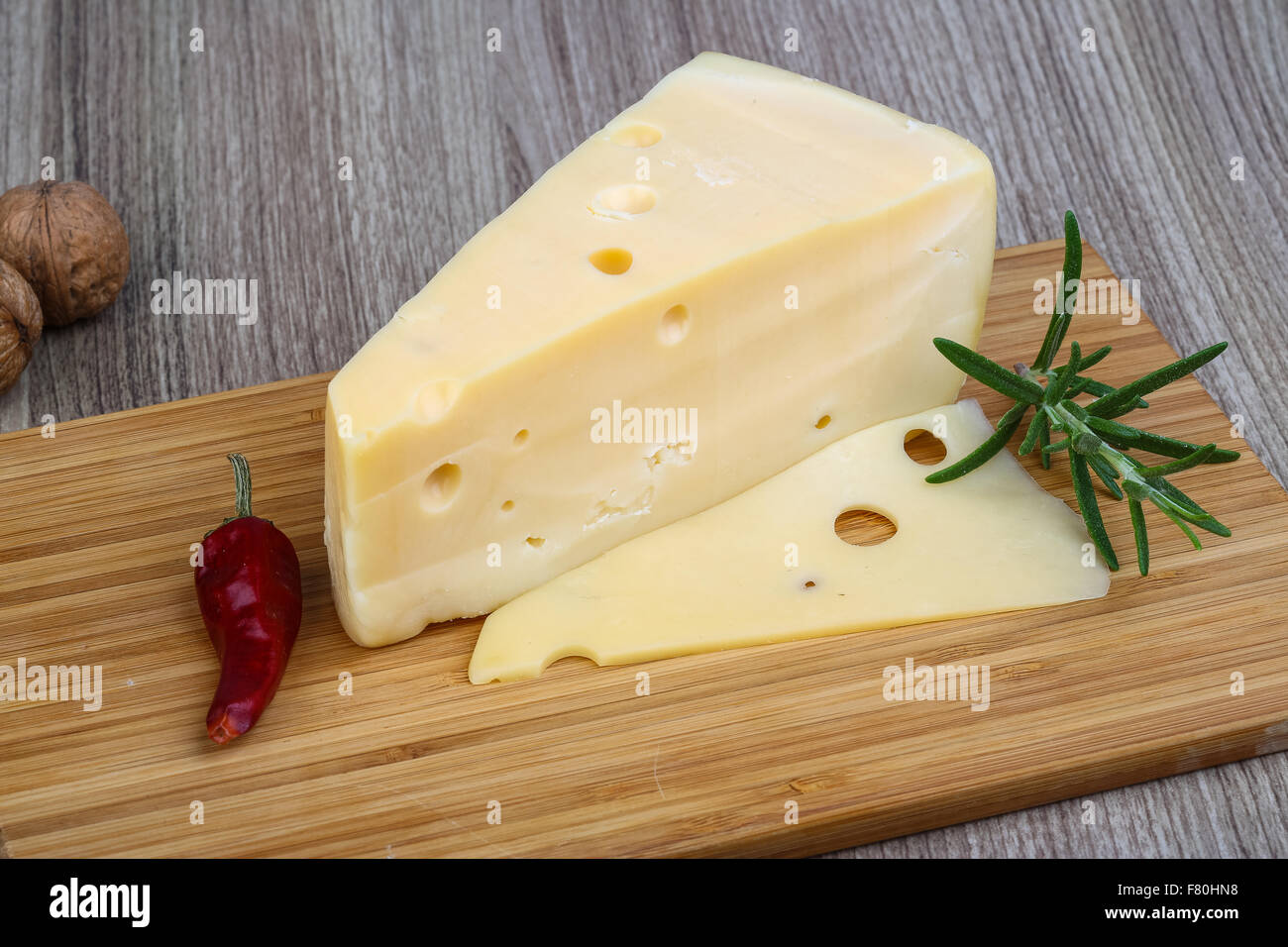 Triangle yellow cheese with rosemary, pepper and salad leaves Stock ...