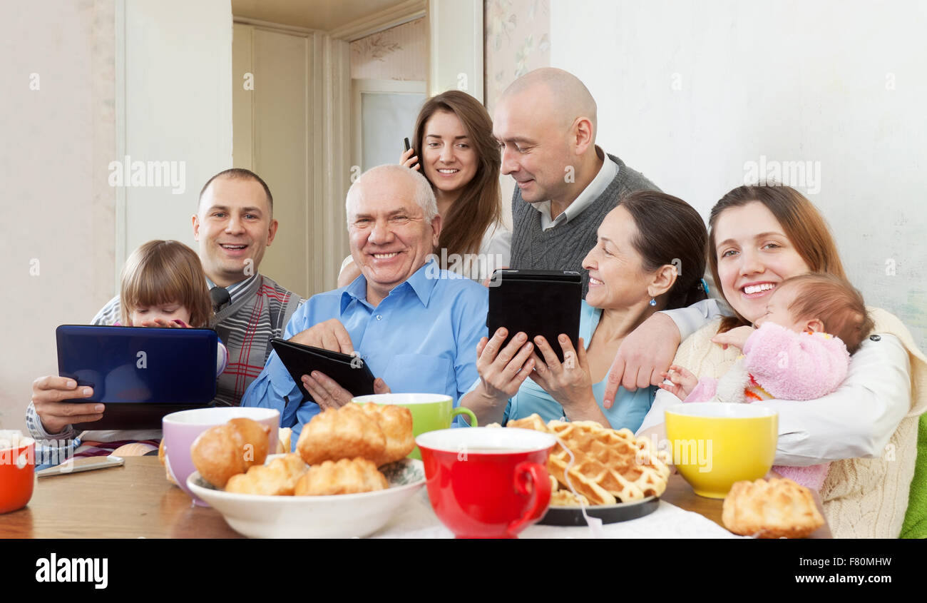 Happy family of three generations or group of friends with electronic ...