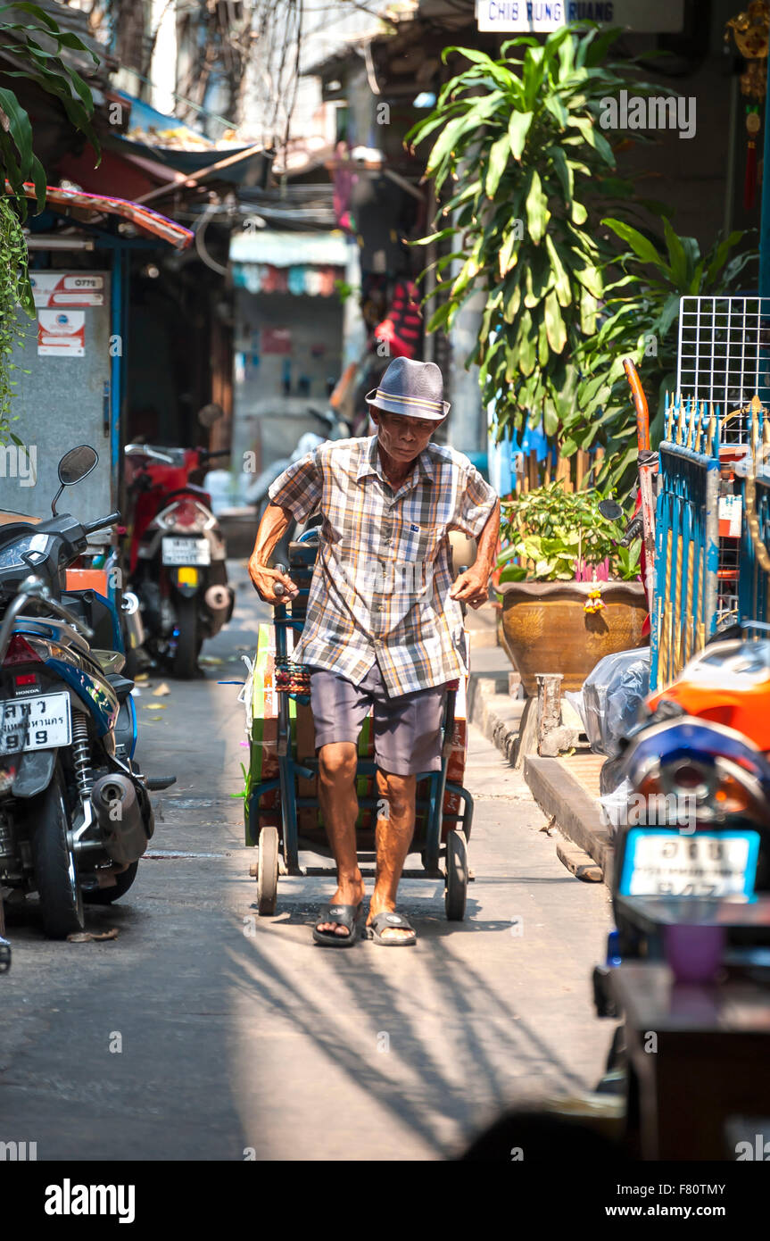 BANGKOK, THAILAND - MARCH 2015 - An elderly porter transporting goods ...