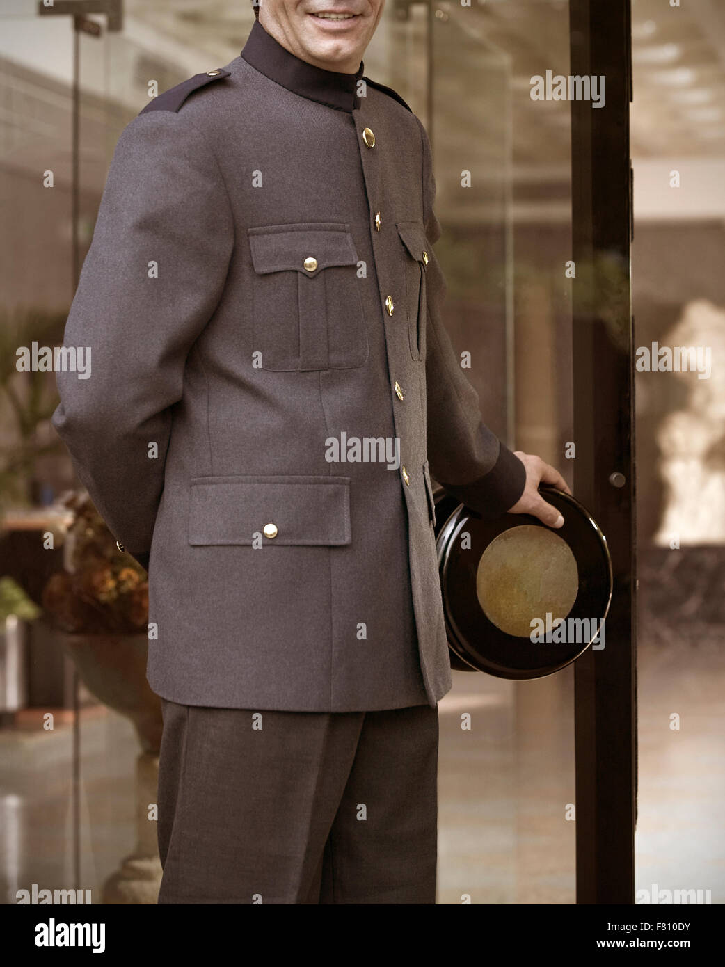 Smiley Bellhop with grey uniform opening Hotel door Stock Photo - Alamy
