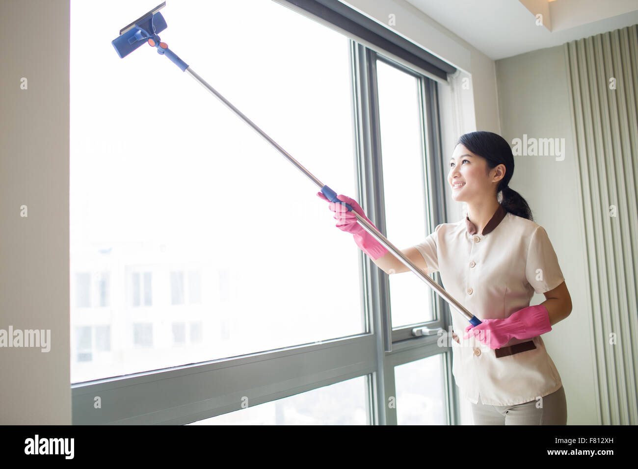 Domestic staff cleaning the window Stock Photo - Alamy