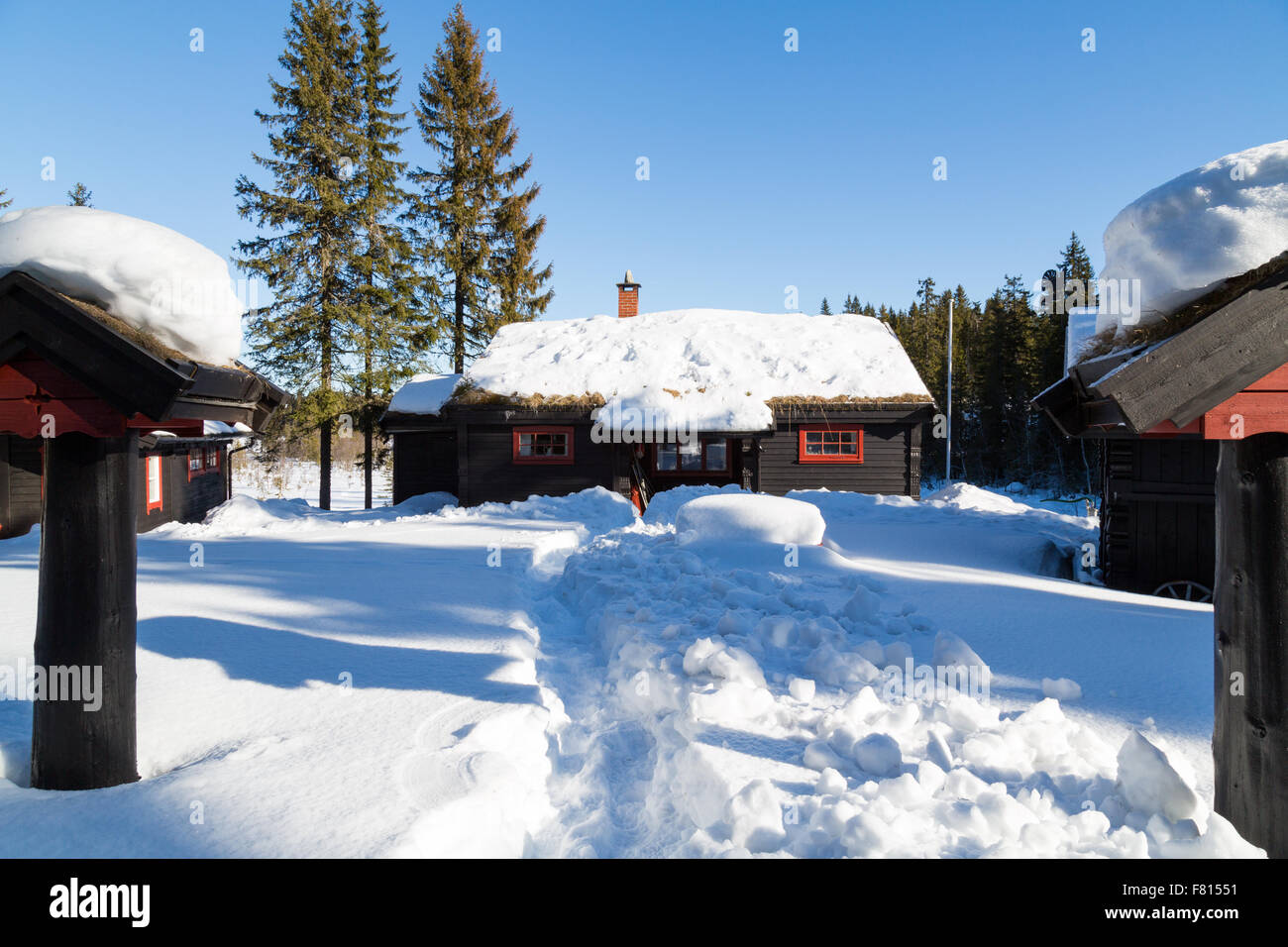 Typical black Norwegian cabin surrounded by deep snow in the forest ...