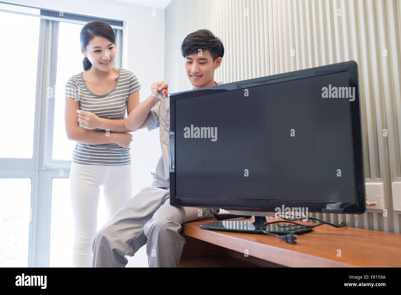 Engineer repairing television in customer's home Stock Photo - Alamy