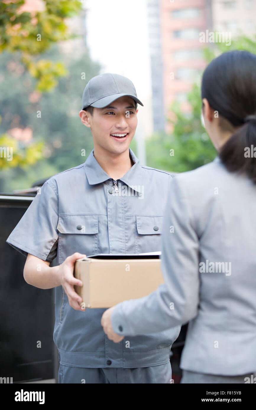 Young woman getting a package from delivery person Stock Photo - Alamy