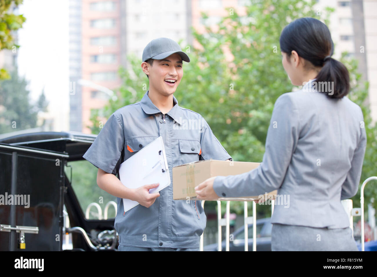 Young woman getting a package from delivery person Stock Photo - Alamy