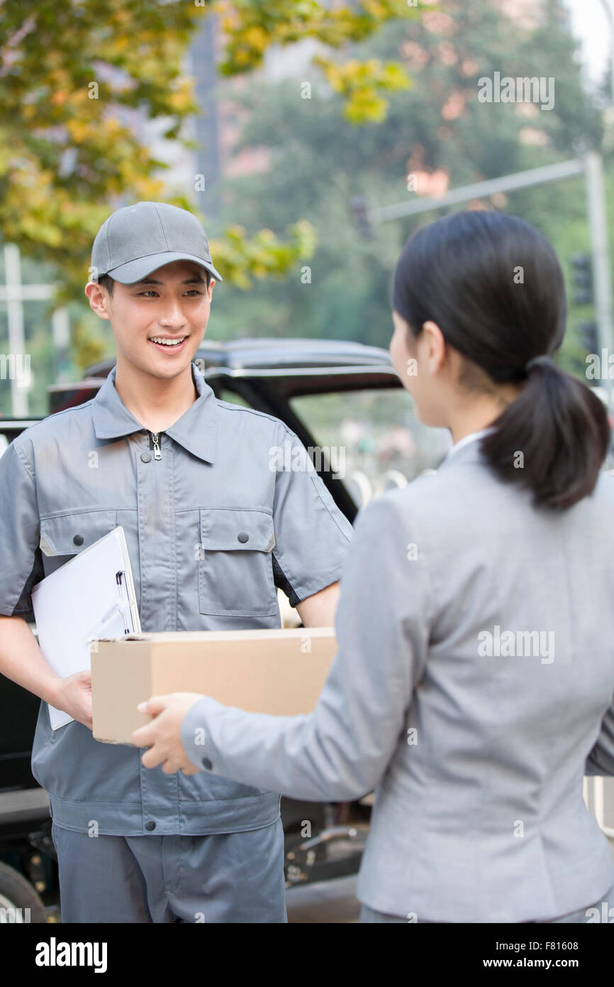 Young woman getting a package from delivery person Stock Photo - Alamy