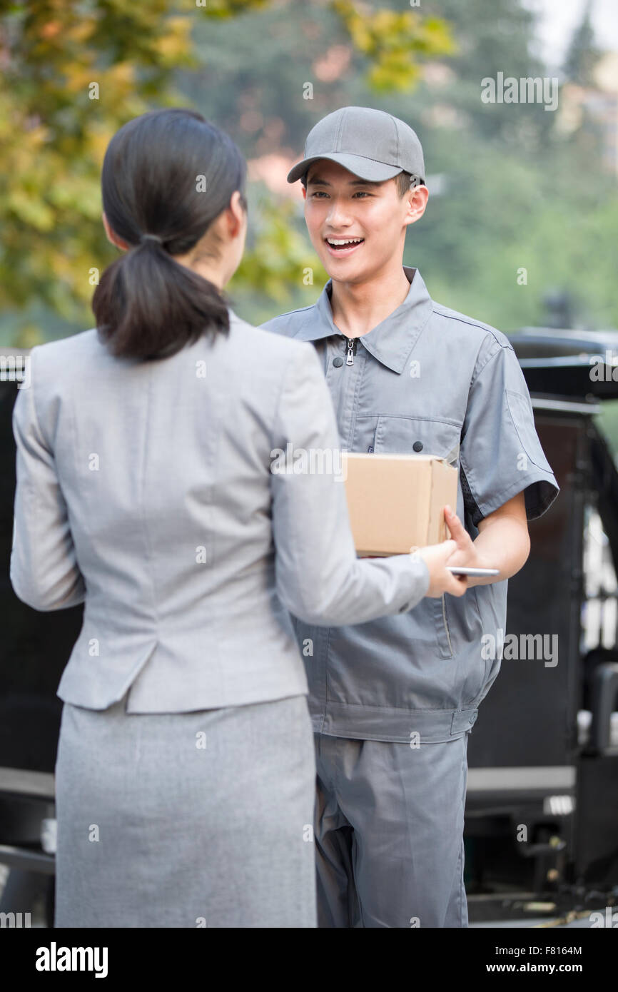 Young woman getting a package from delivery person Stock Photo - Alamy
