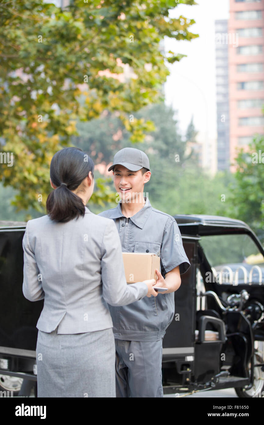 Young woman getting a package from delivery person Stock Photo - Alamy
