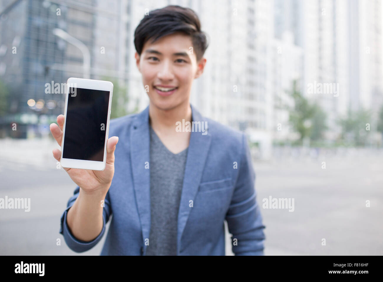 Confident young man showing smart phone Stock Photo - Alamy