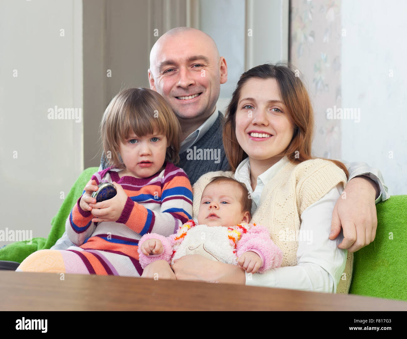Happy parents with two children at home interior Stock Photo - Alamy